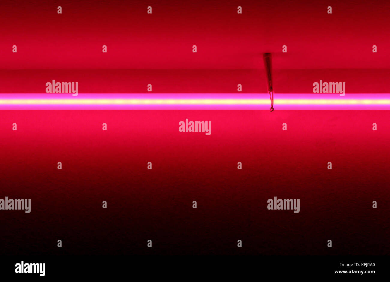 Violet neon tube light glowing on a red background wall Stock Photo - Alamy