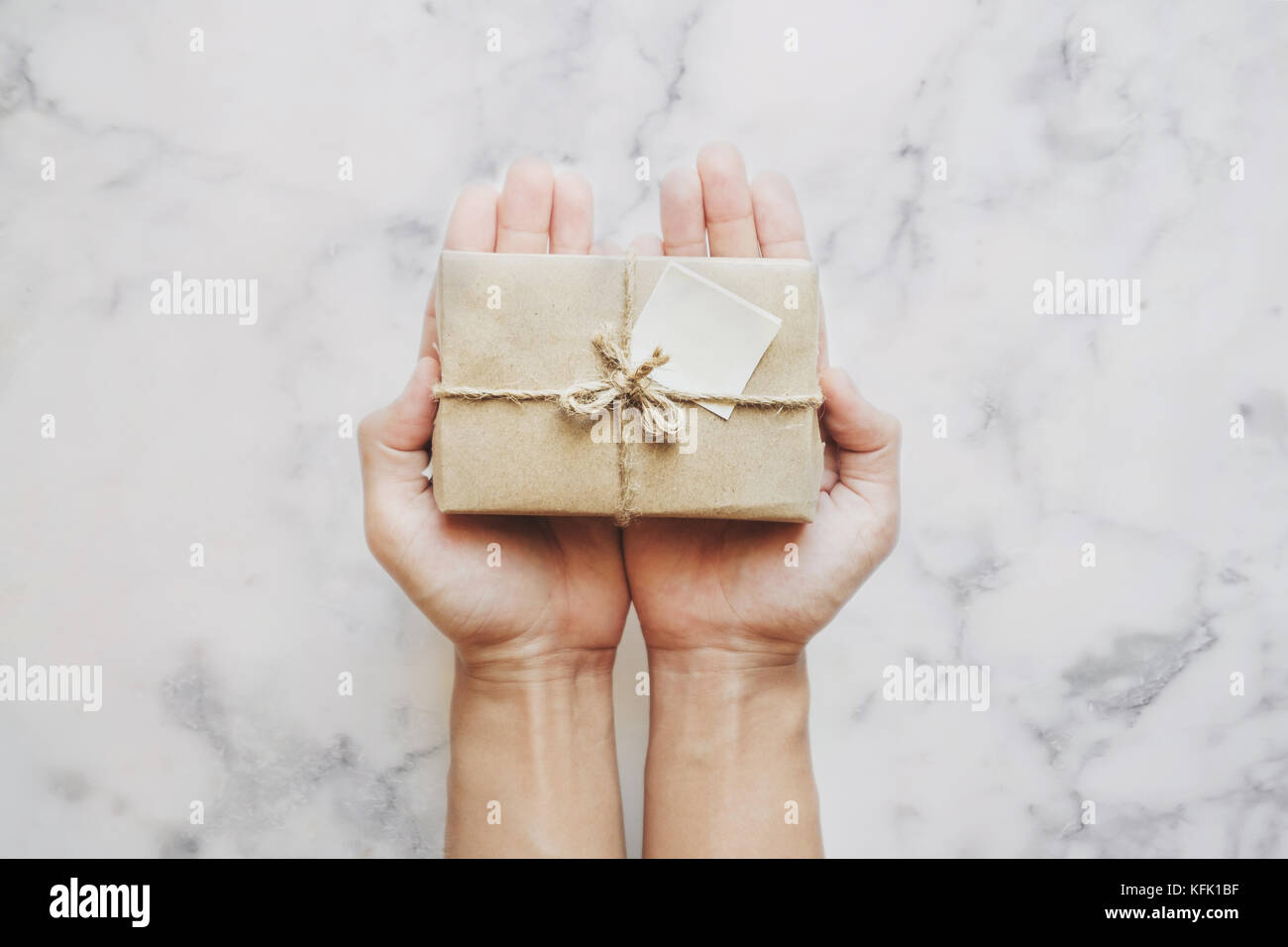 Hand holding parcel gift box, on white marble stone table background ...