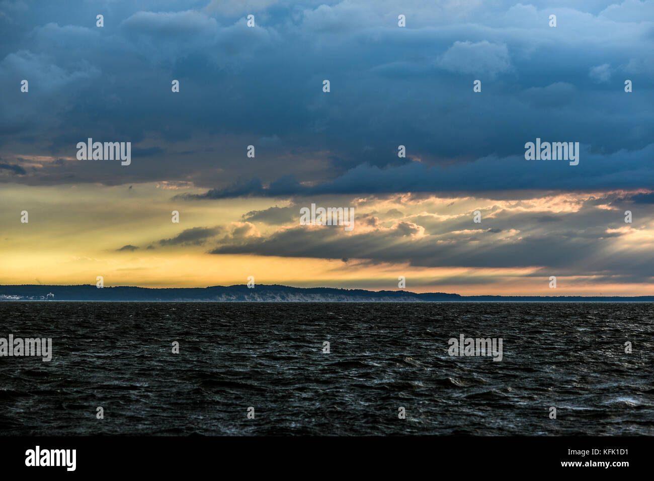 German coast with clouds and yellow sun on the horizon in the Baltic ...