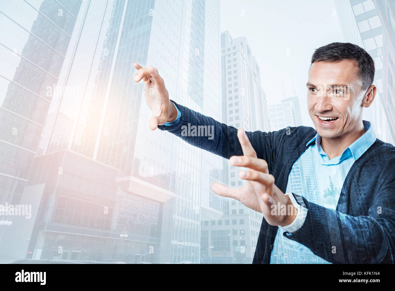 Happy pleasant man holding a virtual object Stock Photo - Alamy