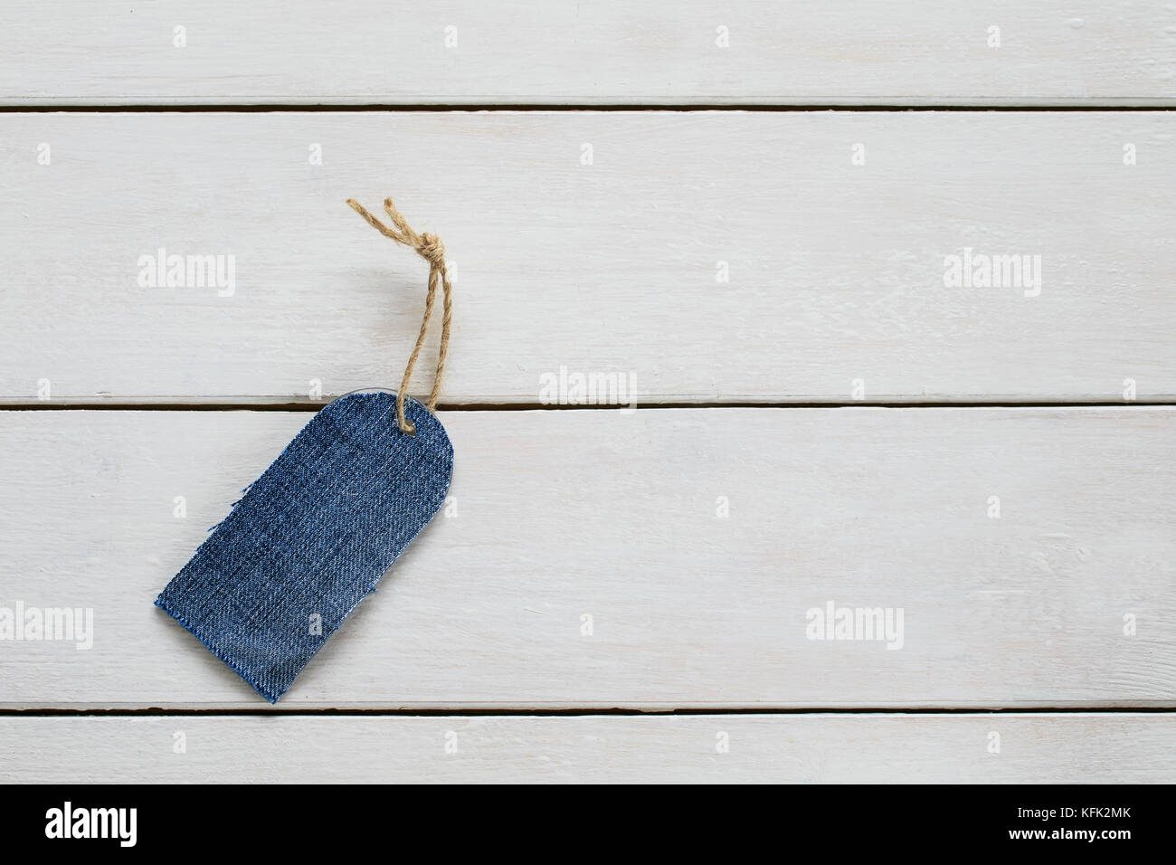 stylish blank price tag of denim on a string is on a white painted ...