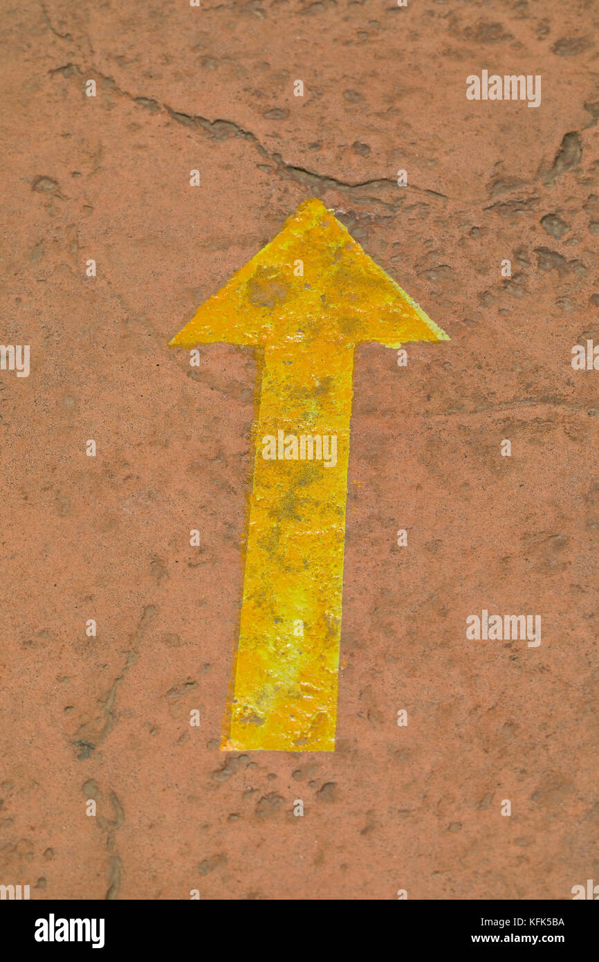 Yellow arrow painted onto a path showing the direction Stock Photo - Alamy