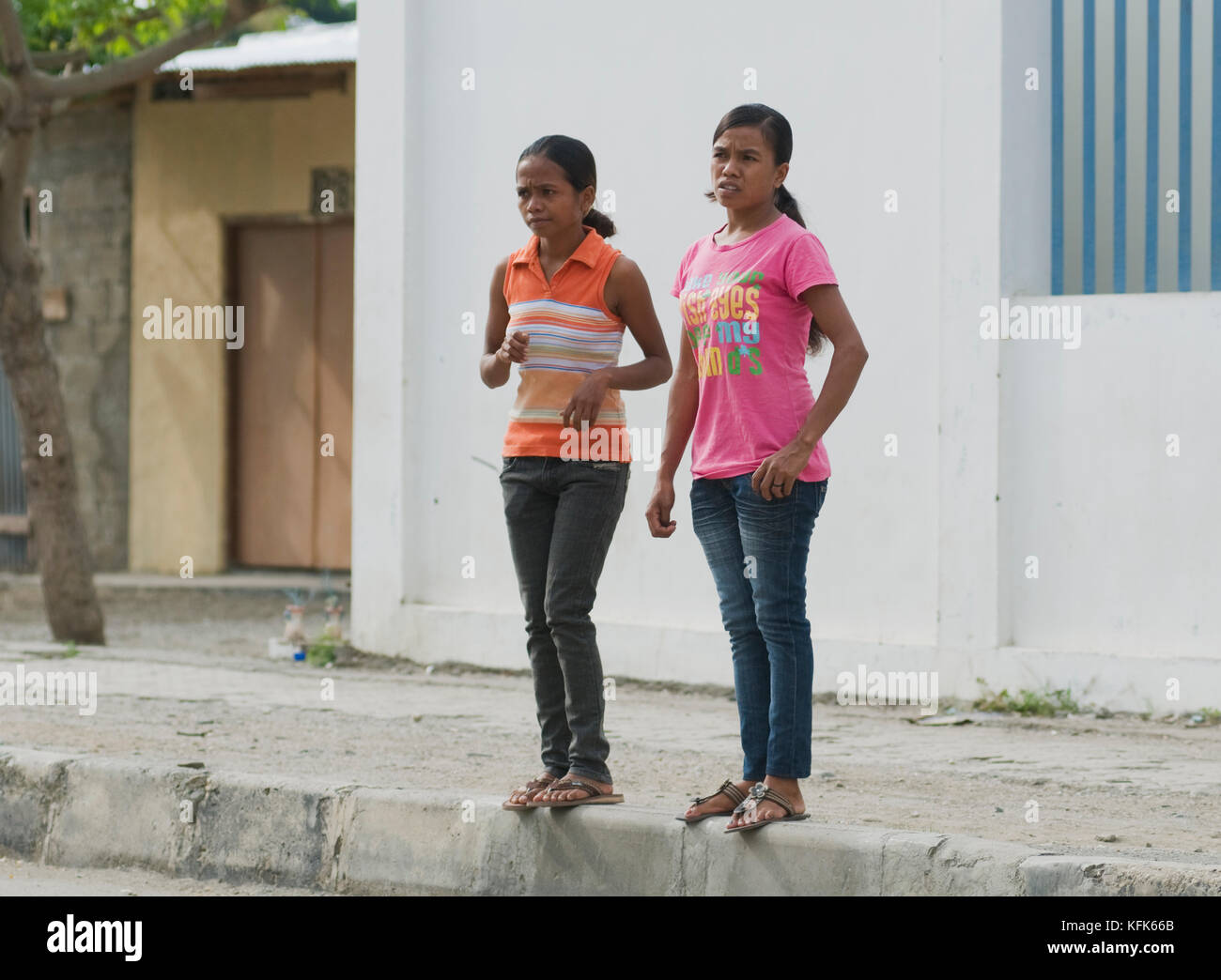 Two girls wait to cross a busy street in Dili, Timor-Leste (East Timor ...