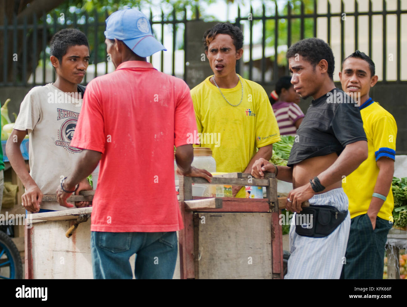 Men gather around a street vendor selling a variety of foods from a ...