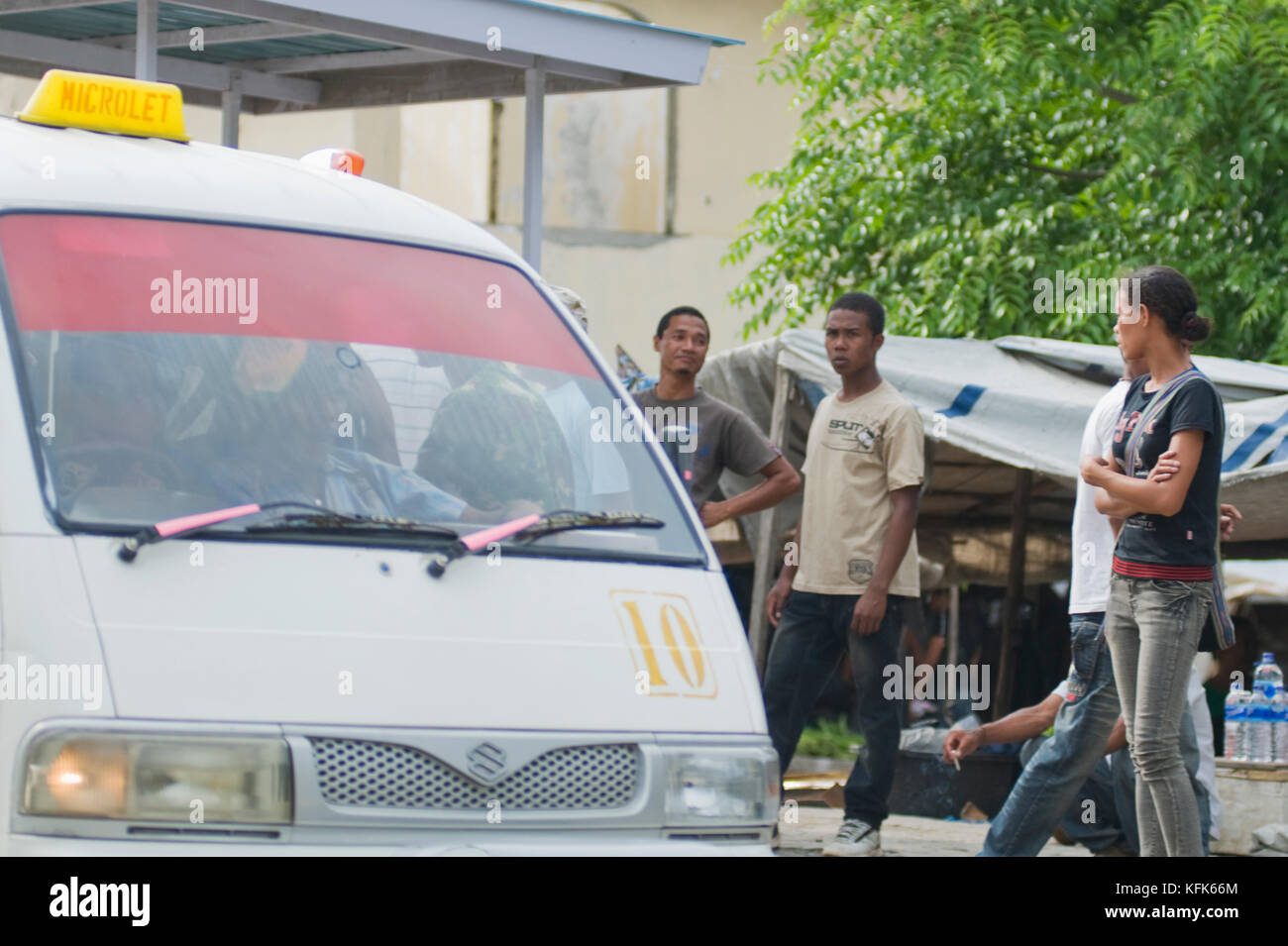 Passengers wait to board a microlet (minibus) on a busy street in Dili ...