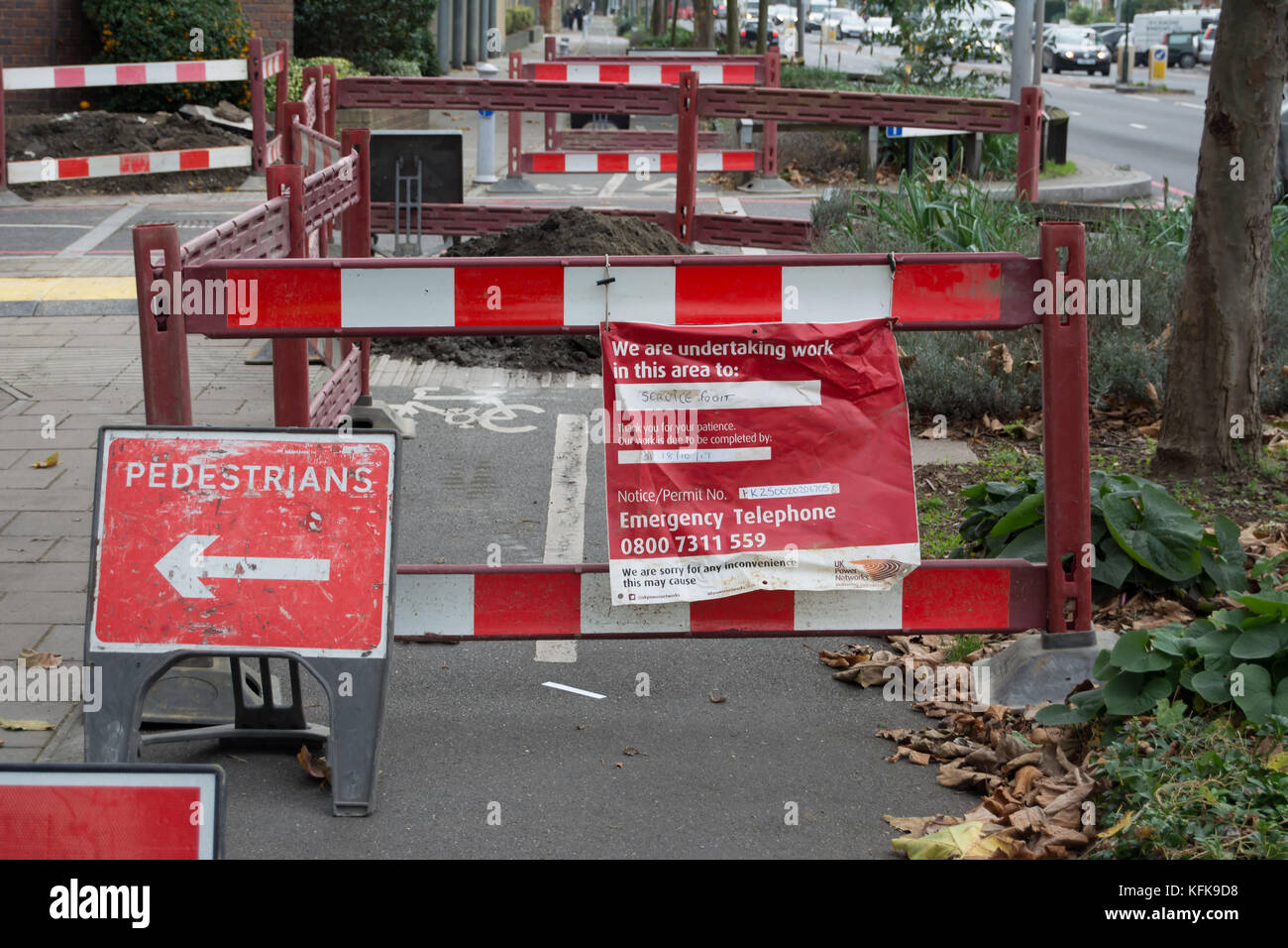 red and white barriers and a pedestrian redirection sign at street ...