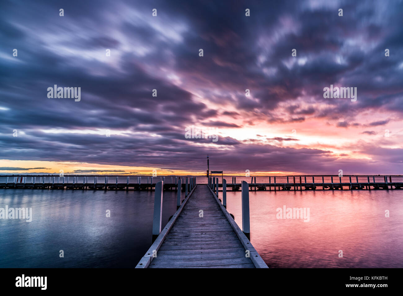 Jetty during sunrise, with lilac/purple colours and a cloudy sky Stock ...