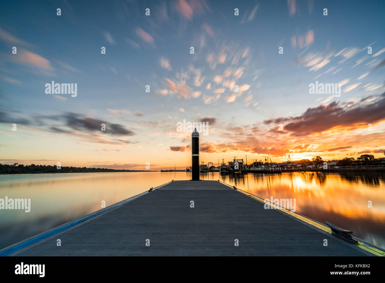 Jetty during sunrise, directing the gaze to the horizon. A single mast ...