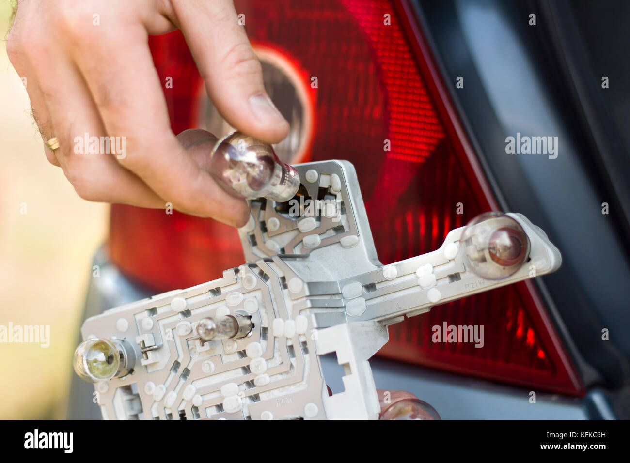 The mechanic's hand inserts the bulb into the frame rear lamp of the ...
