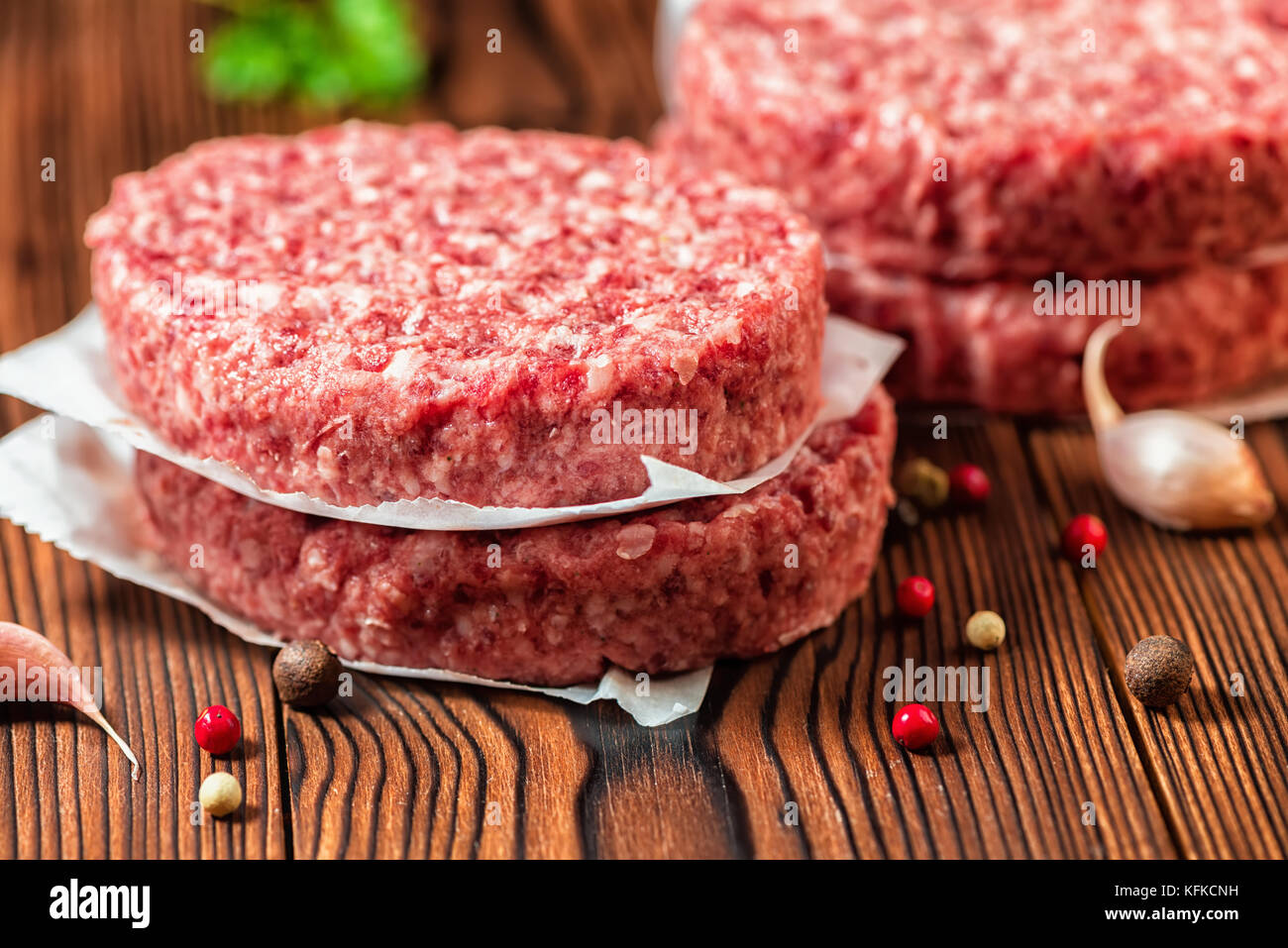 raw beef meat burger steak cutlets, dry pepper and garlic on rural ...