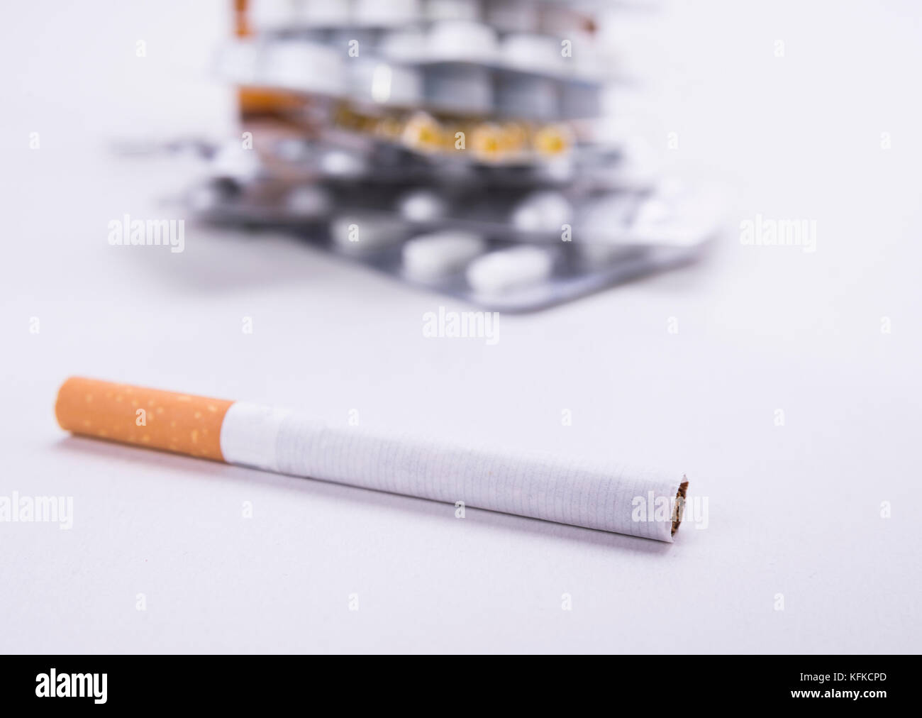 Cigarette on the white background against pills. Smoking ruins your ...