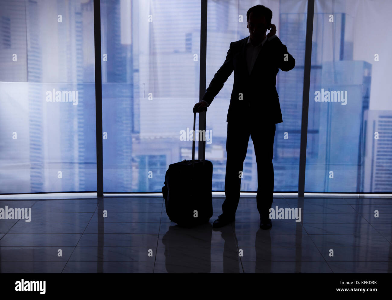 Full length rear view of businessman with luggage using cell phone by ...