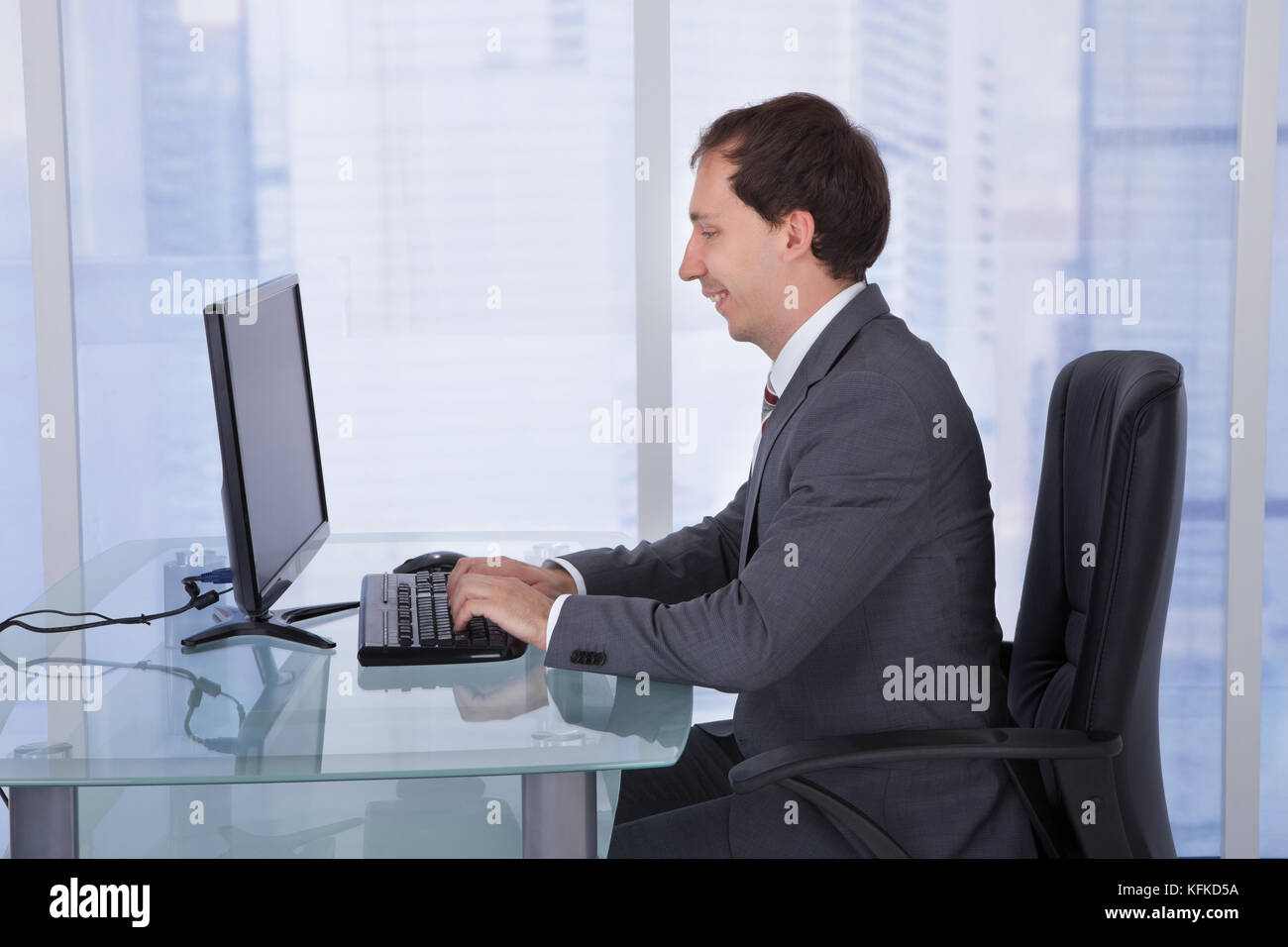 Side view of mid adult businessman working on computer at desk in ...
