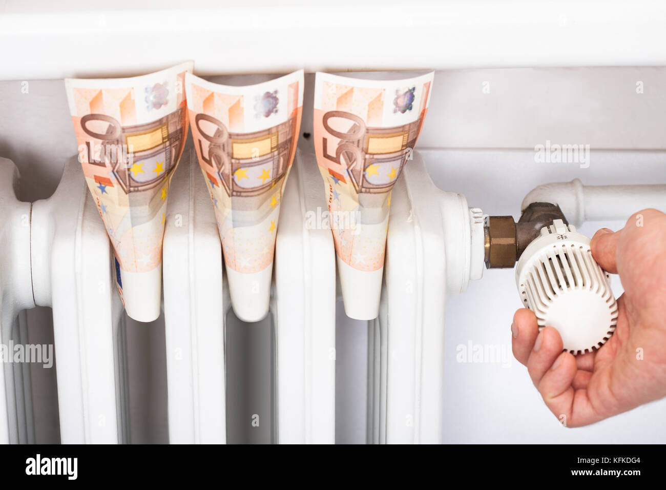 Euro banknotes stuck in radiator with man adjusting thermostat Stock ...