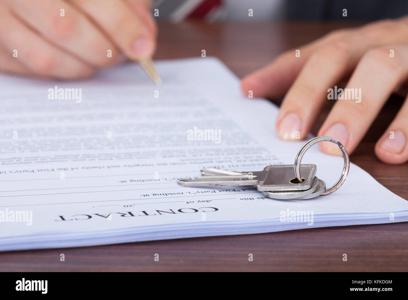 Cropped image of man signing contract with keys on it Stock Photo - Alamy