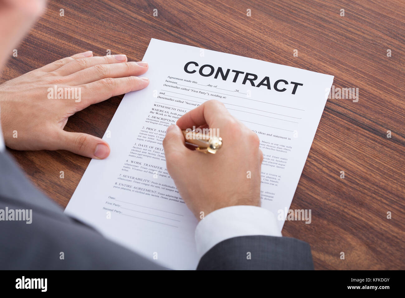 Cropped image of businessman signing contract at table Stock Photo - Alamy