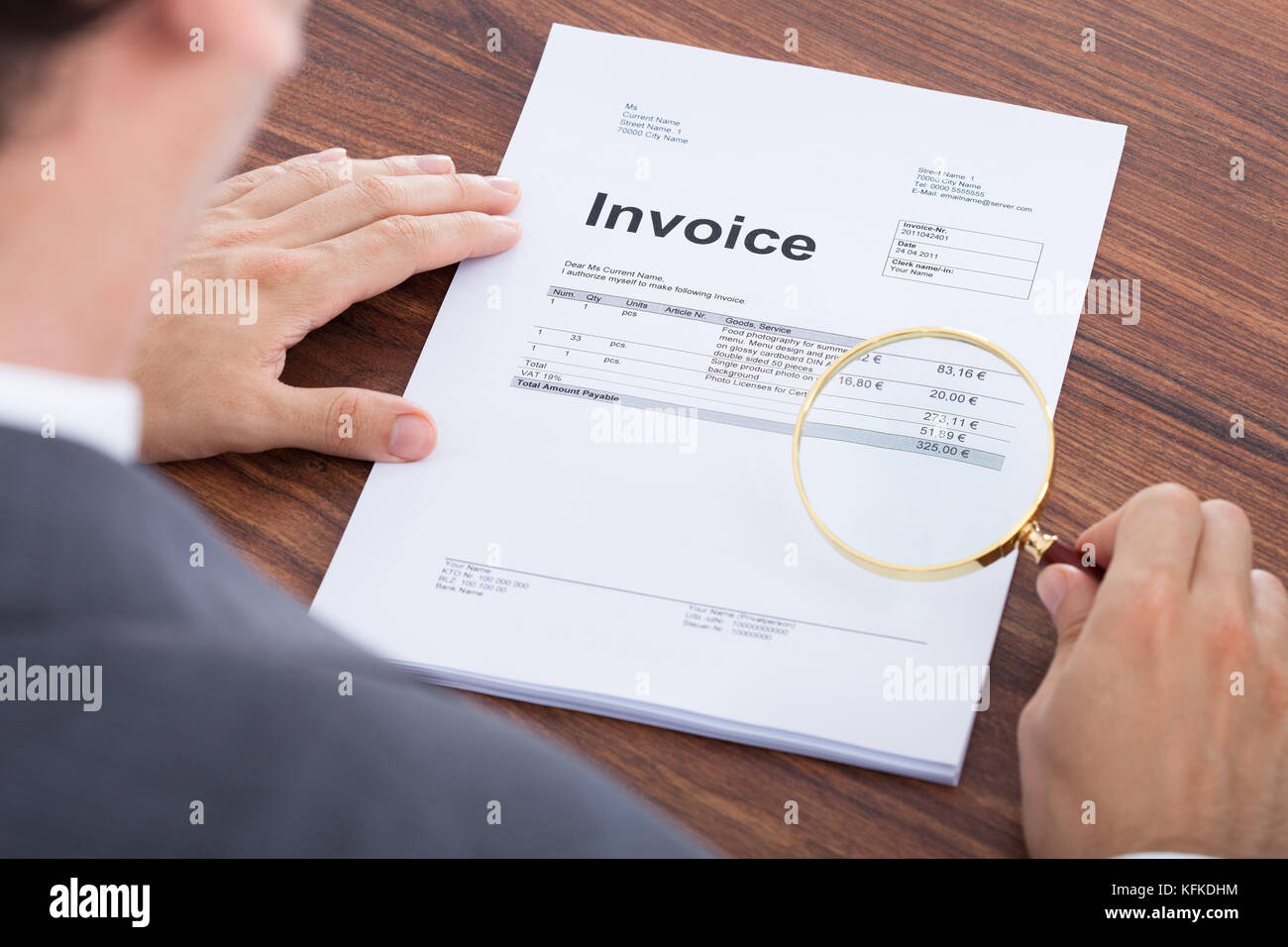 Cropped image of businessman examining invoice with magnifying glass at ...