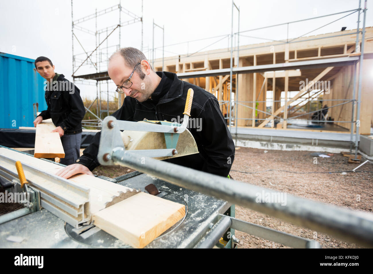 Carpenter Cutting Wood Using Table Saw While Colleague Assisting Stock ...