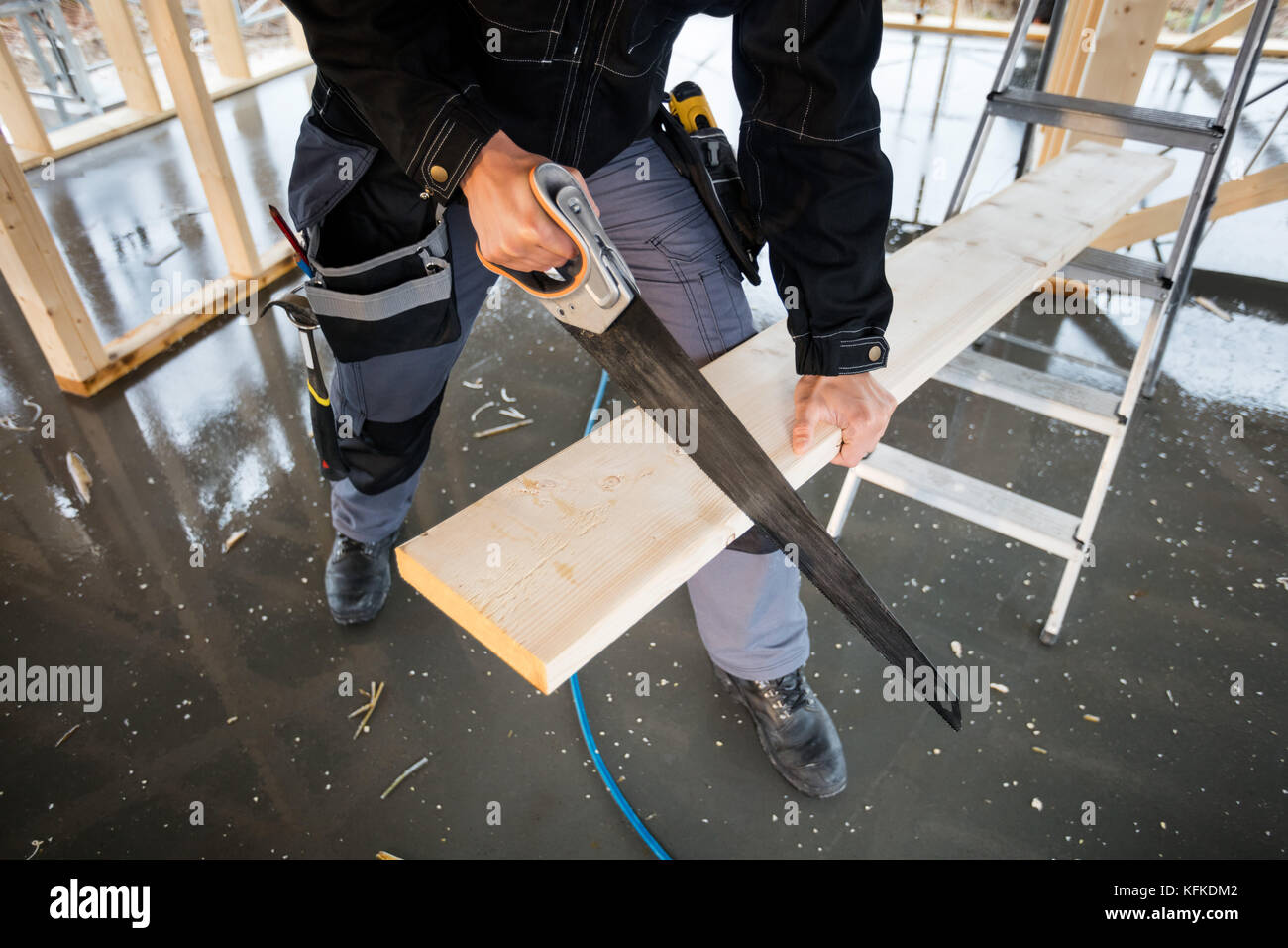 Low Section Of Carpenter Using Hand Saw To Cut Plank Stock Photo - Alamy