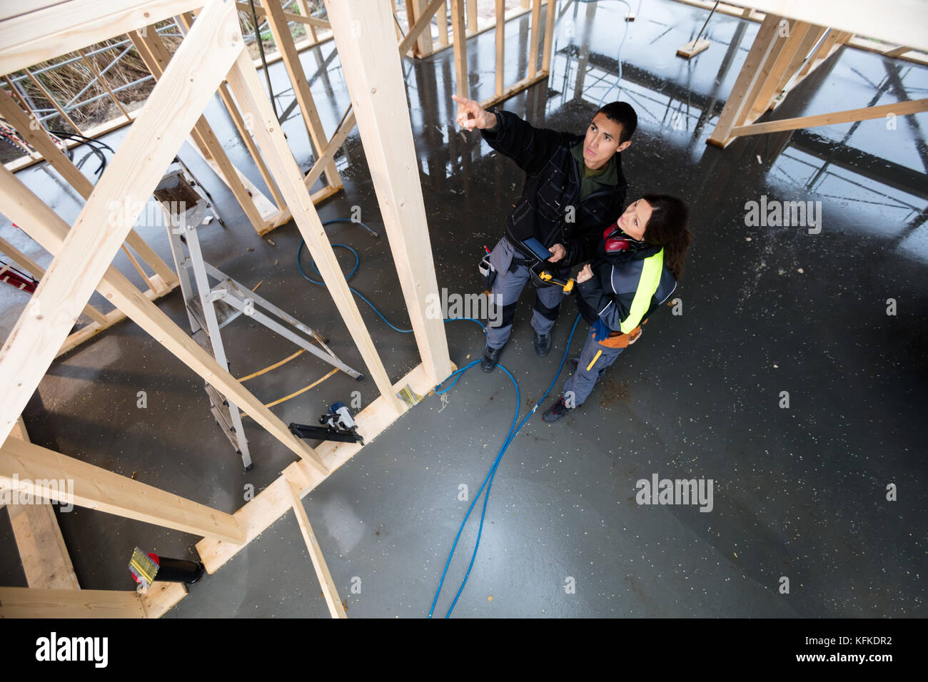 Carpenter Pointing By Female Colleague In Incomplete Architectur Stock ...