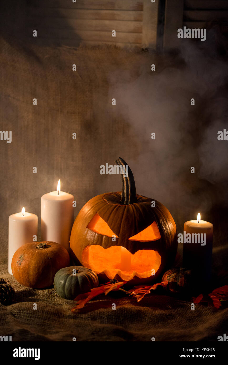 Scary jack-o-lantern, red leaves and candles Stock Photo - Alamy