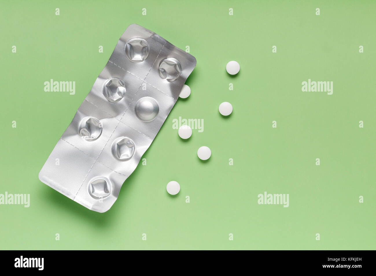 Foil blister pack with round pills on green background Stock Photo - Alamy