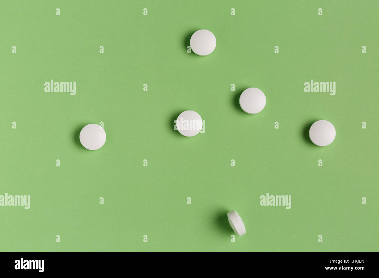 White round medicine pills on green background Stock Photo - Alamy