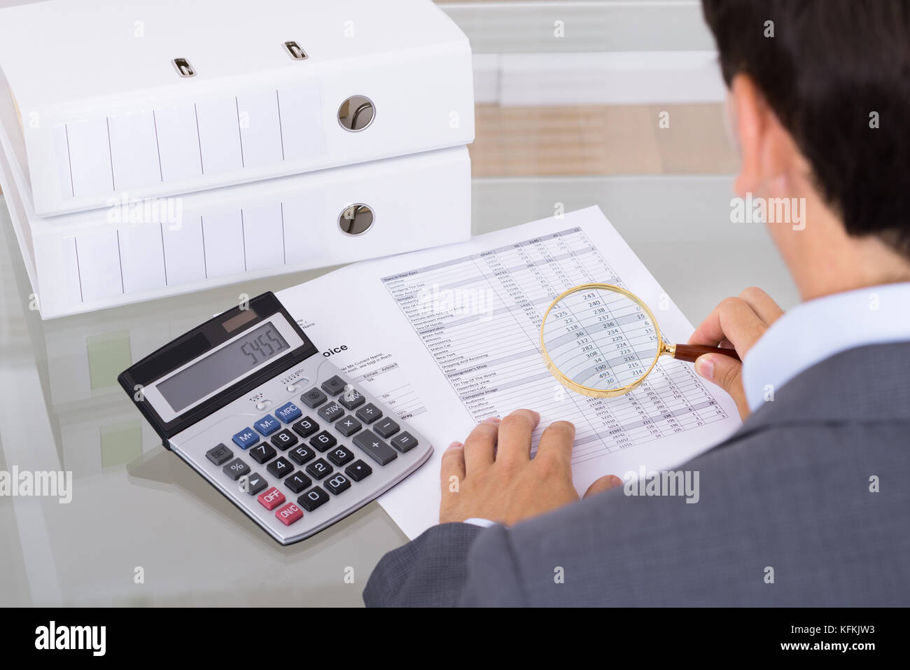 Auditor investigating fraud with magnifying glass. Over the shoulder ...