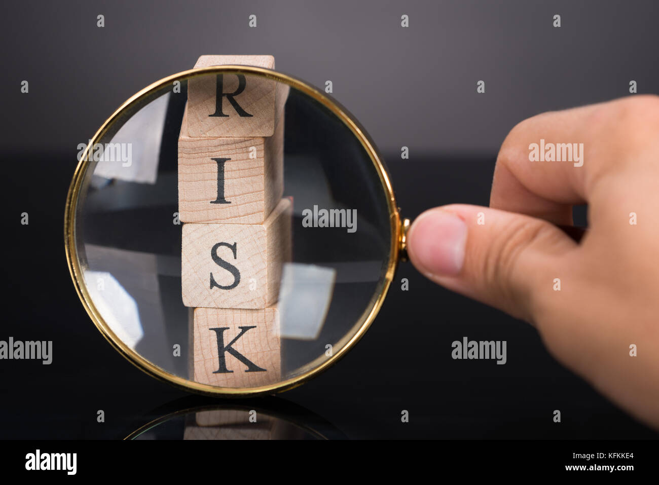 Inspecting risk blocks with loupe over black background Stock Photo - Alamy