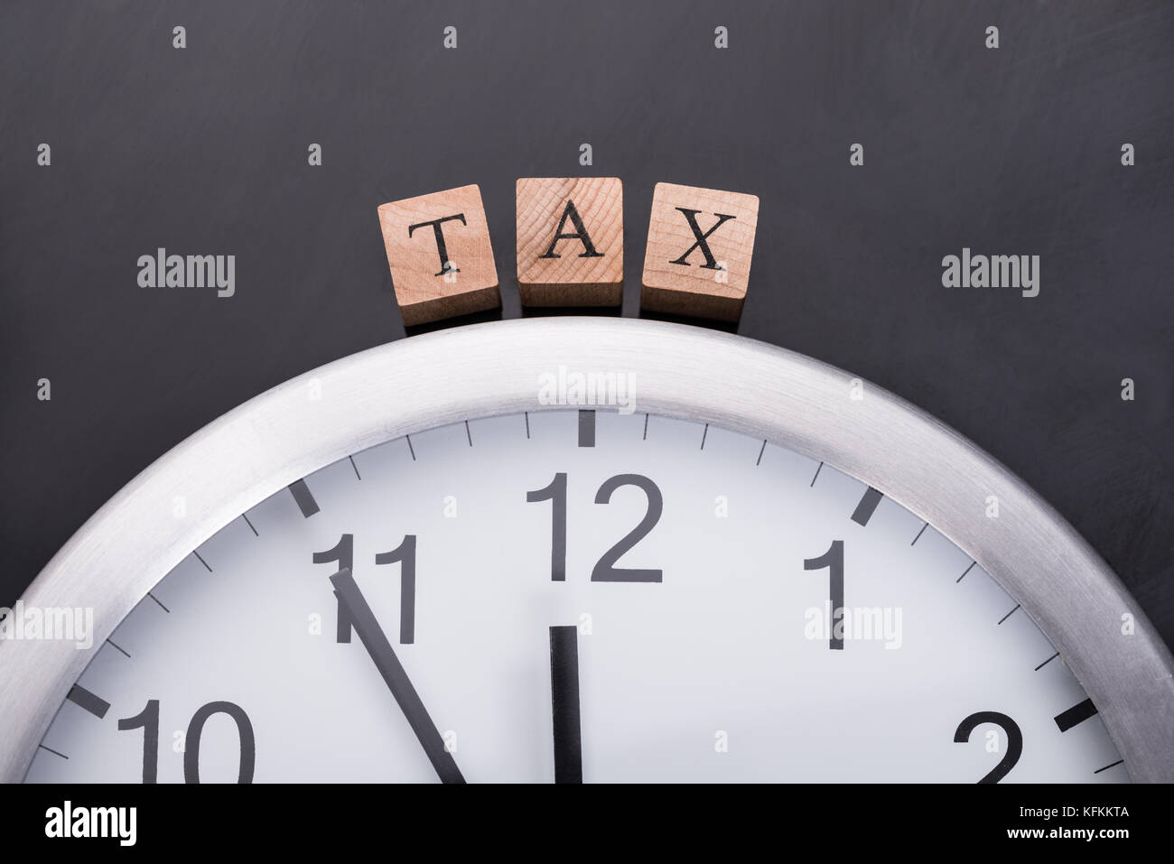 Clock showing tax time on black background Stock Photo - Alamy