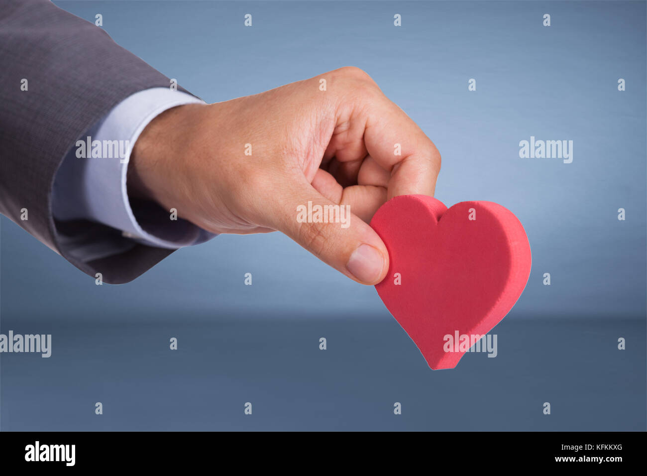 Hand holding heart shape over blue background Stock Photo - Alamy