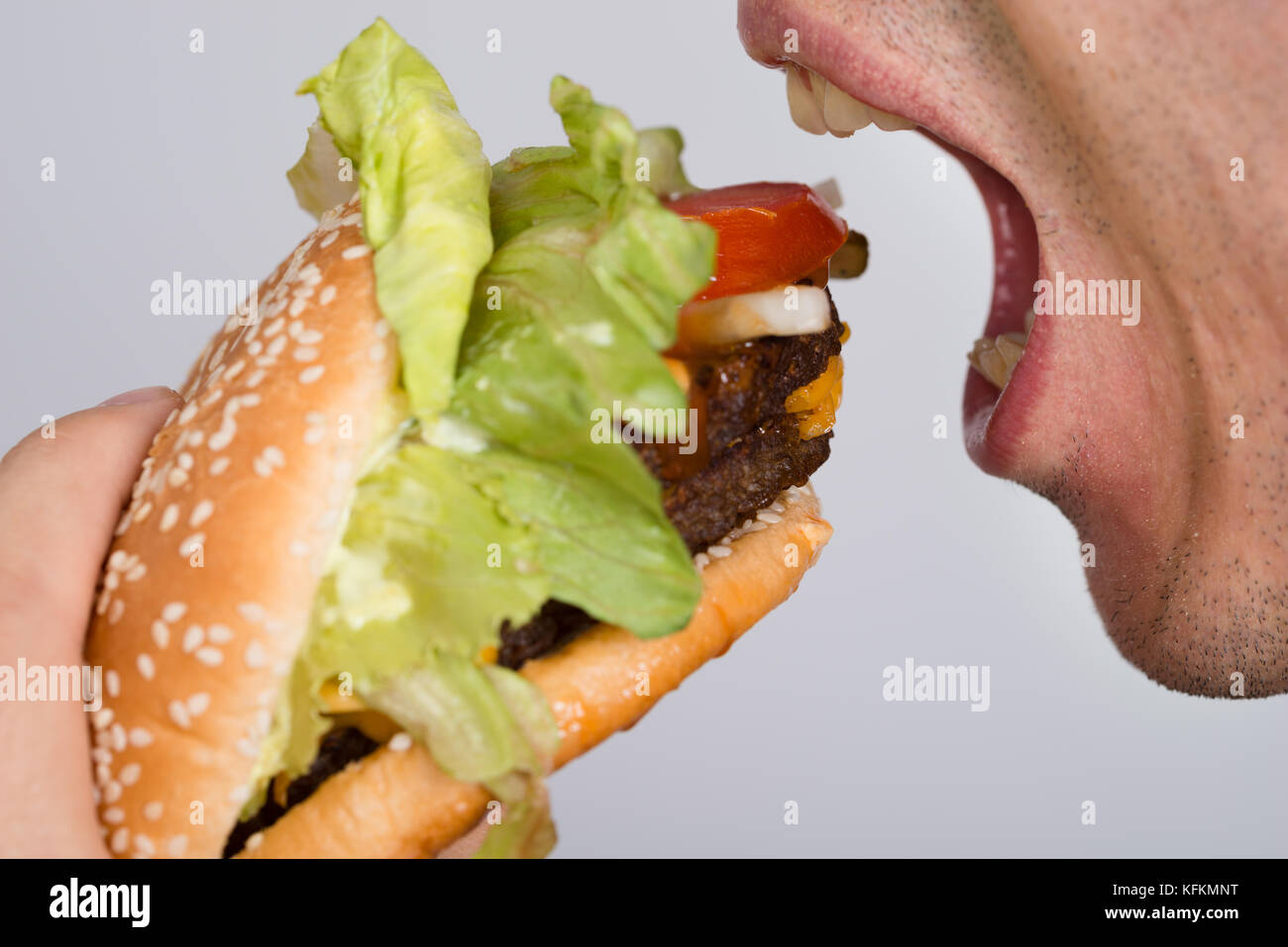 Cropped image of man eating burger against gray background Stock Photo ...