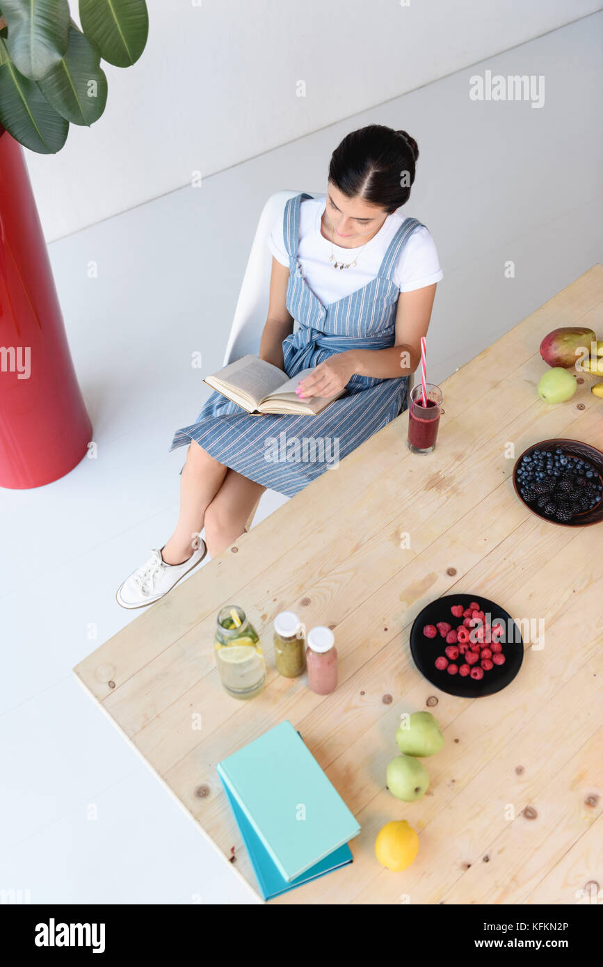 woman reading book at table Stock Photo - Alamy