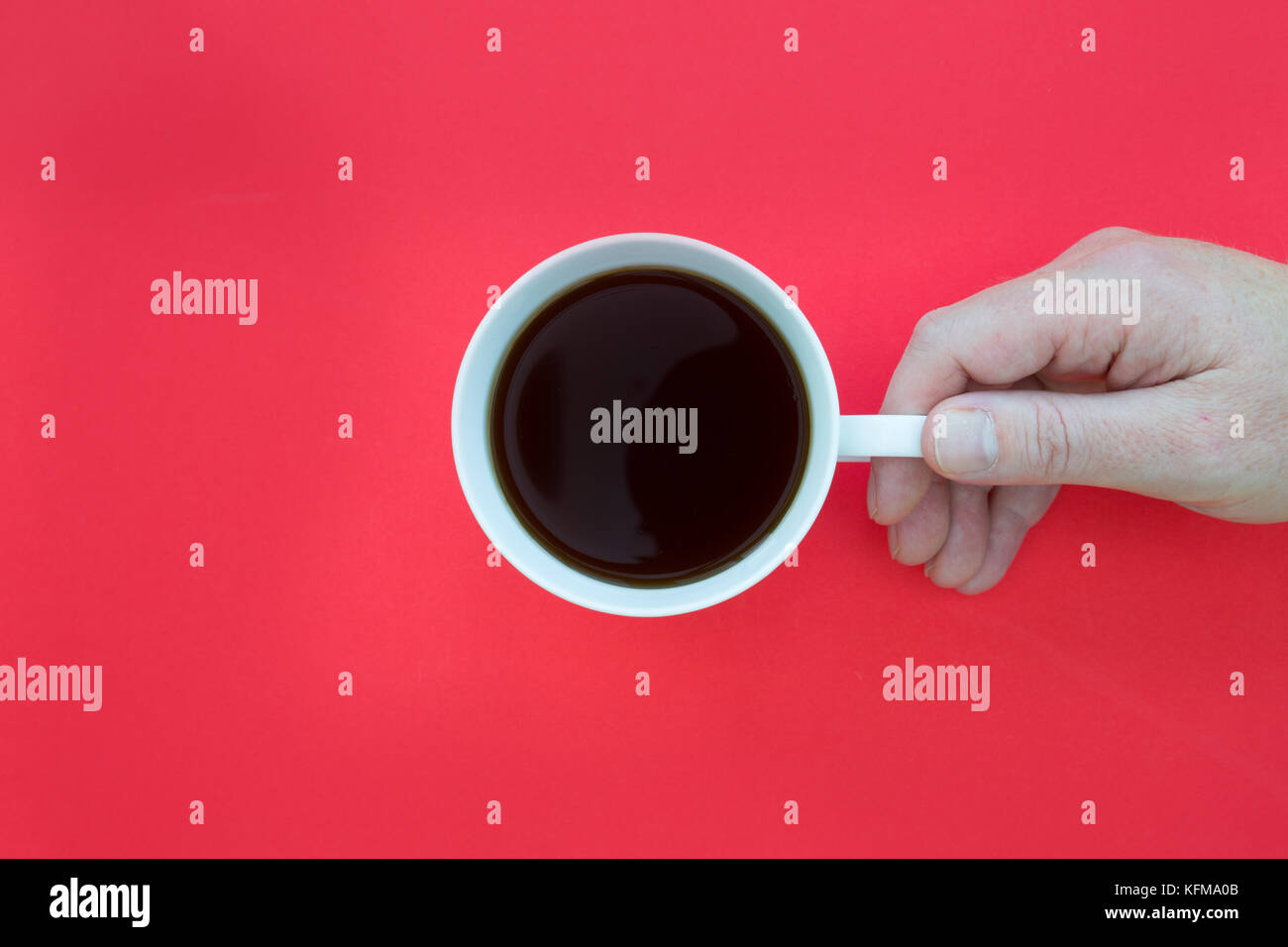 Hand holding coffee cup overhead on bright red background Stock Photo ...