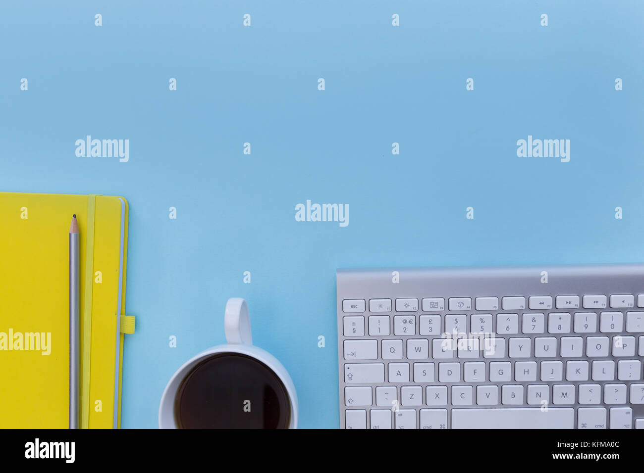Computer keyboard coffee cup and notebook on bright blue background ...