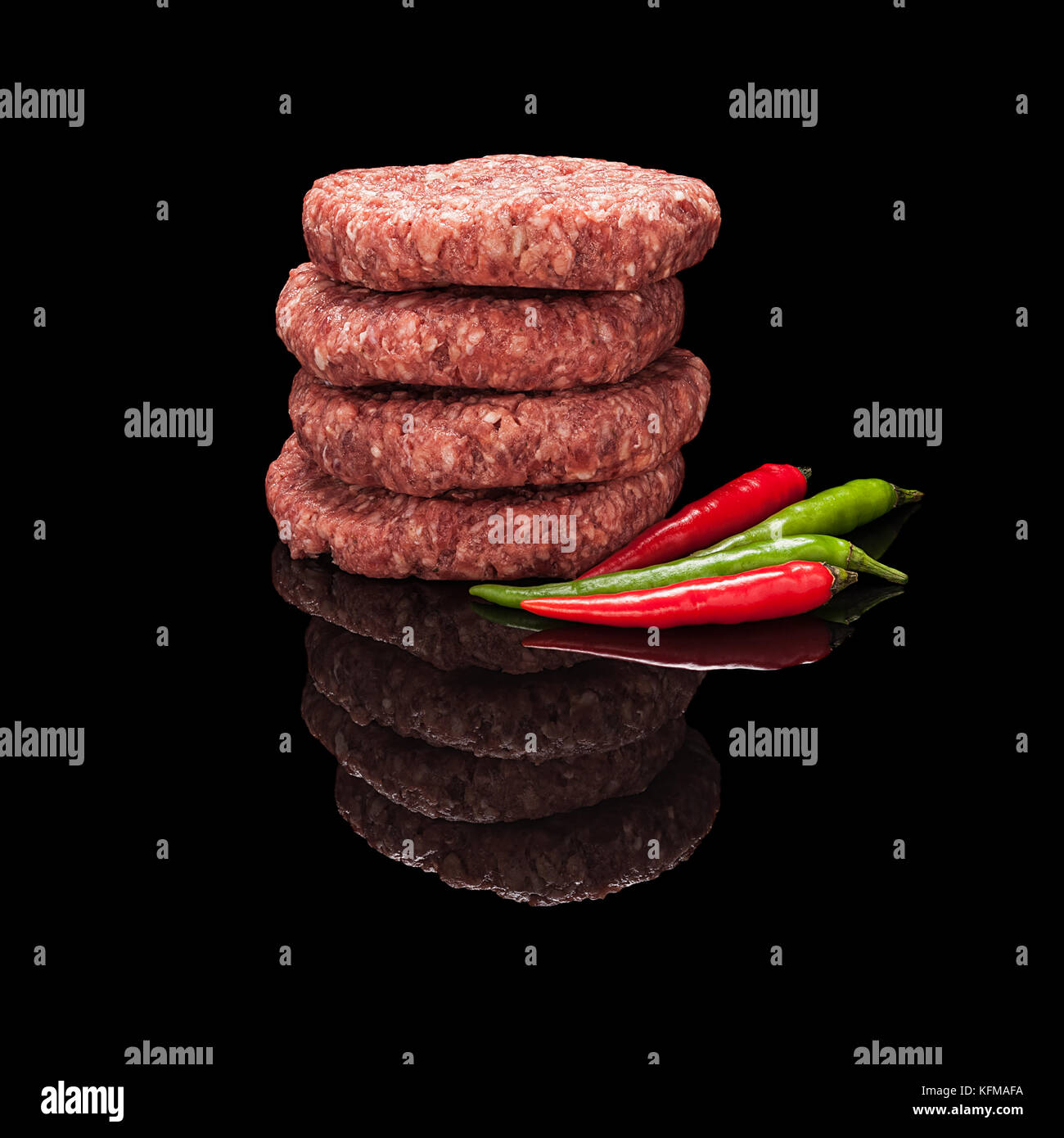 Stack of raw beef patties with hot pepper isolated on black glossy ...
