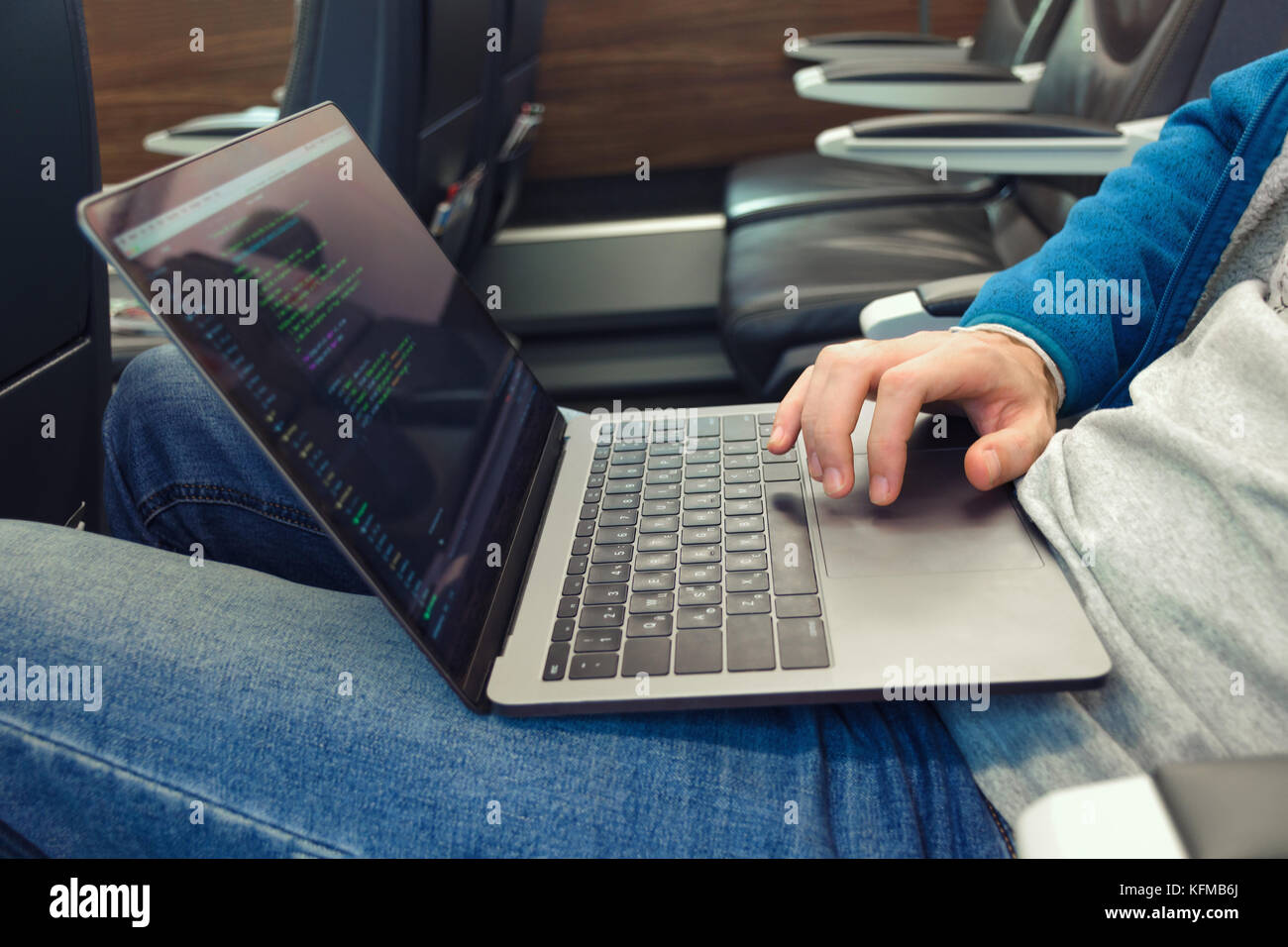 Young man in jeans writing software code on a laptop in a close-up ...