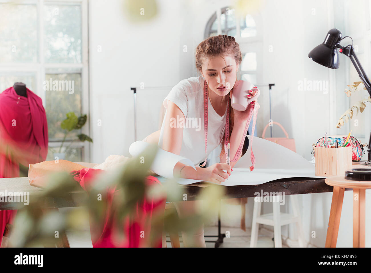 Fashion designers working in studio sitting on the desk Stock Photo - Alamy