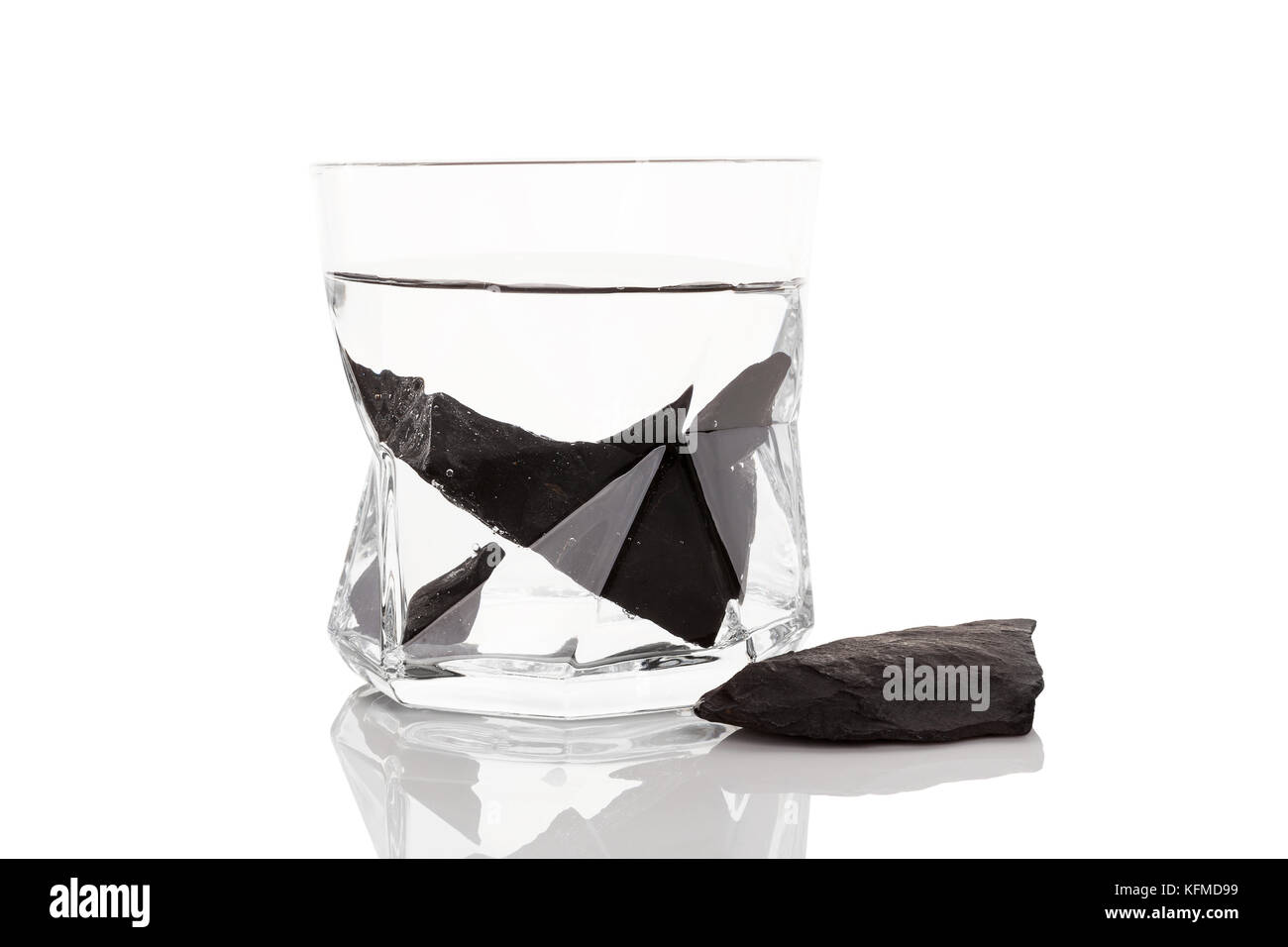 Shungite stones in glass of water isolated on white background. Water ...