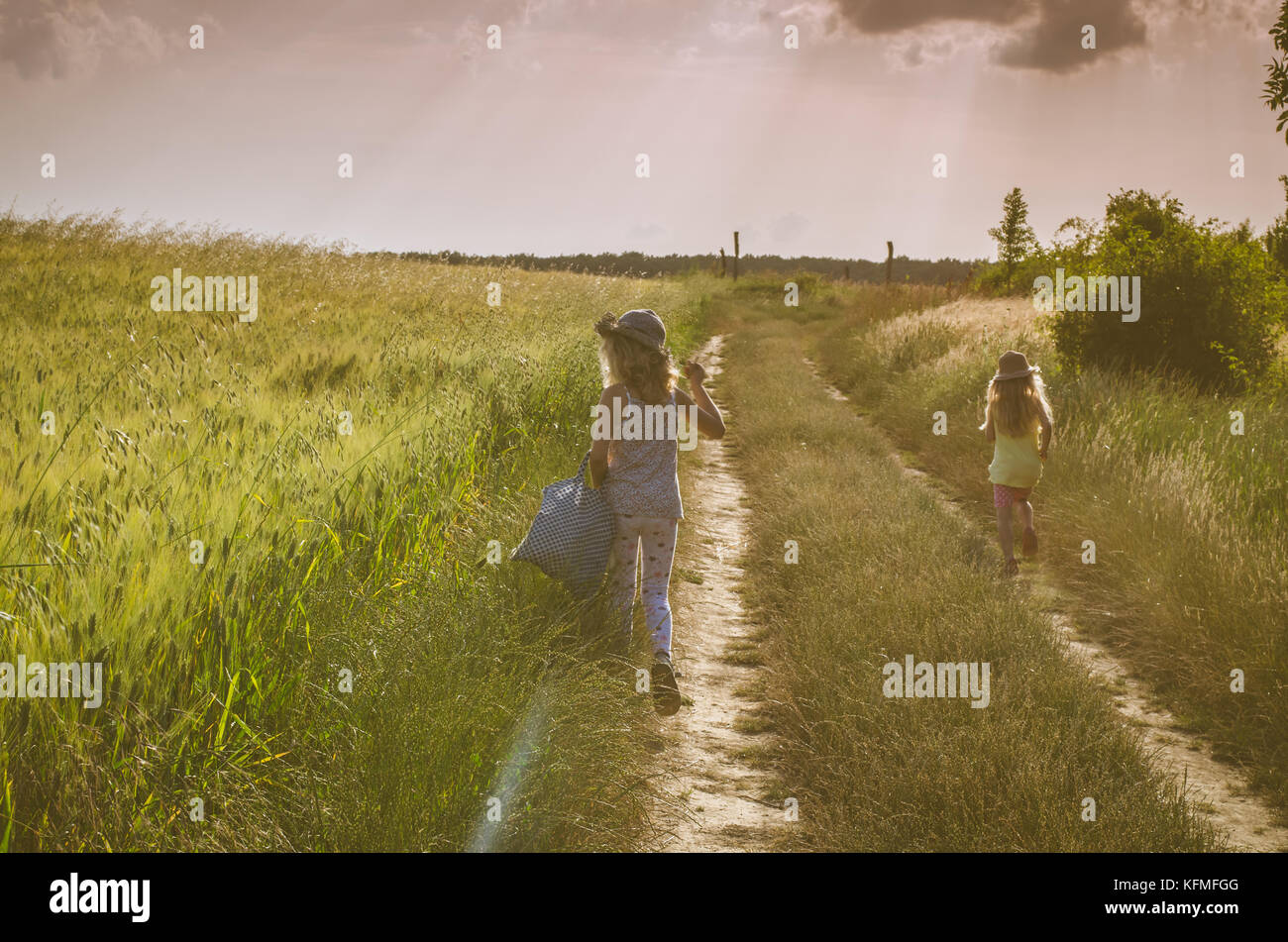 girls walking in romantic colorful rural path among fields Stock Photo ...