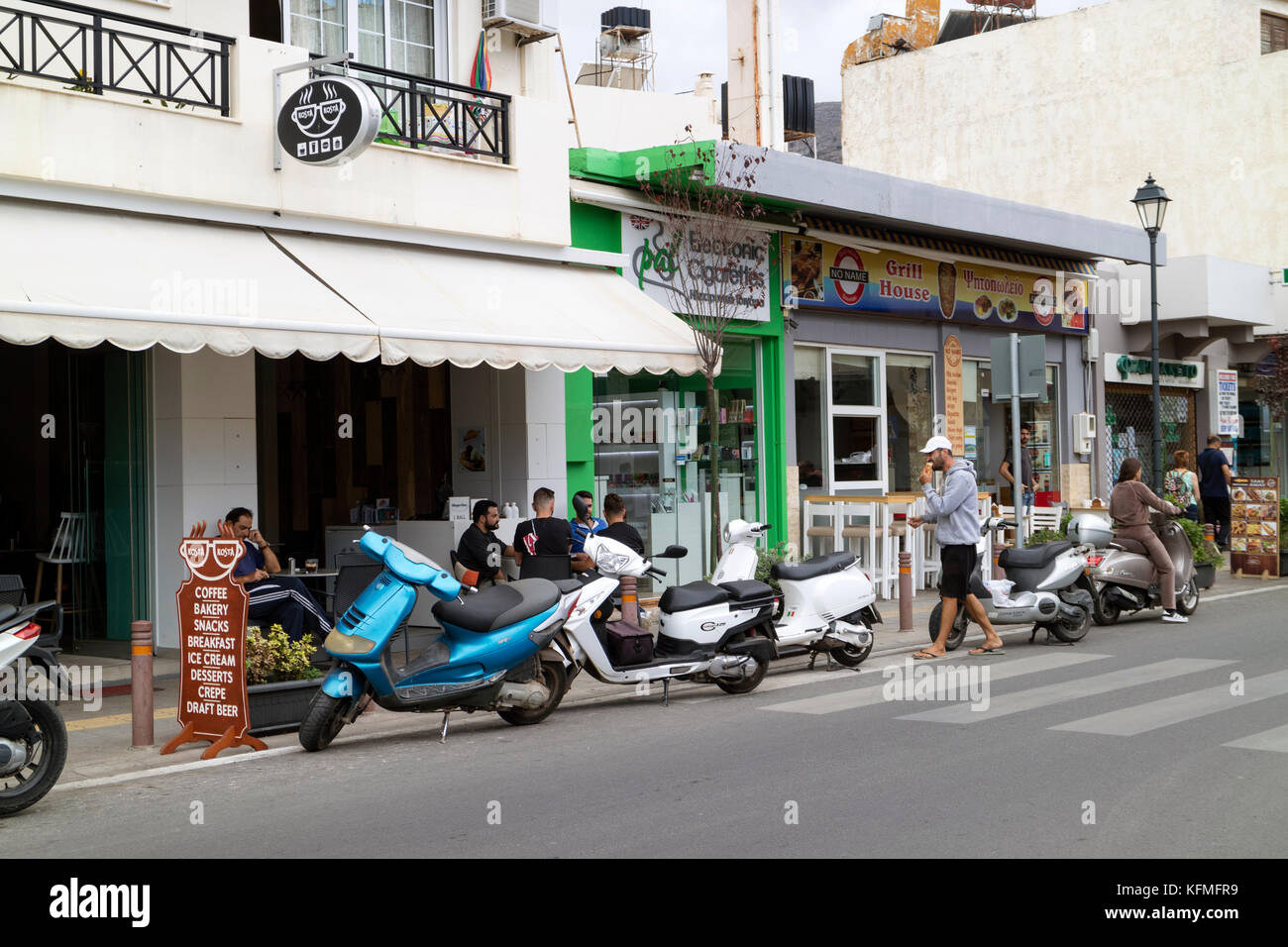 Malia, Crete, Greece. Scooters parked outside shops along the main ...