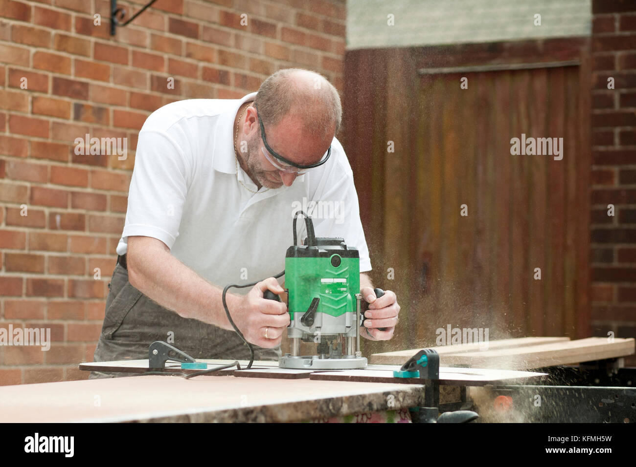 Man cutting kitchen unit top outside residential property using a wood ...