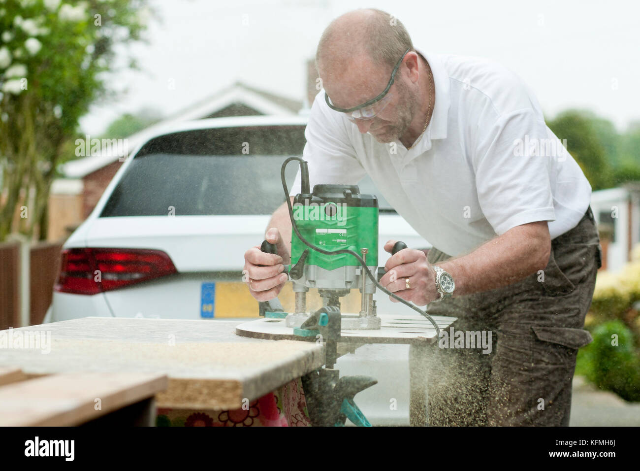 Man cutting kitchen unit top outside residential property using a wood ...