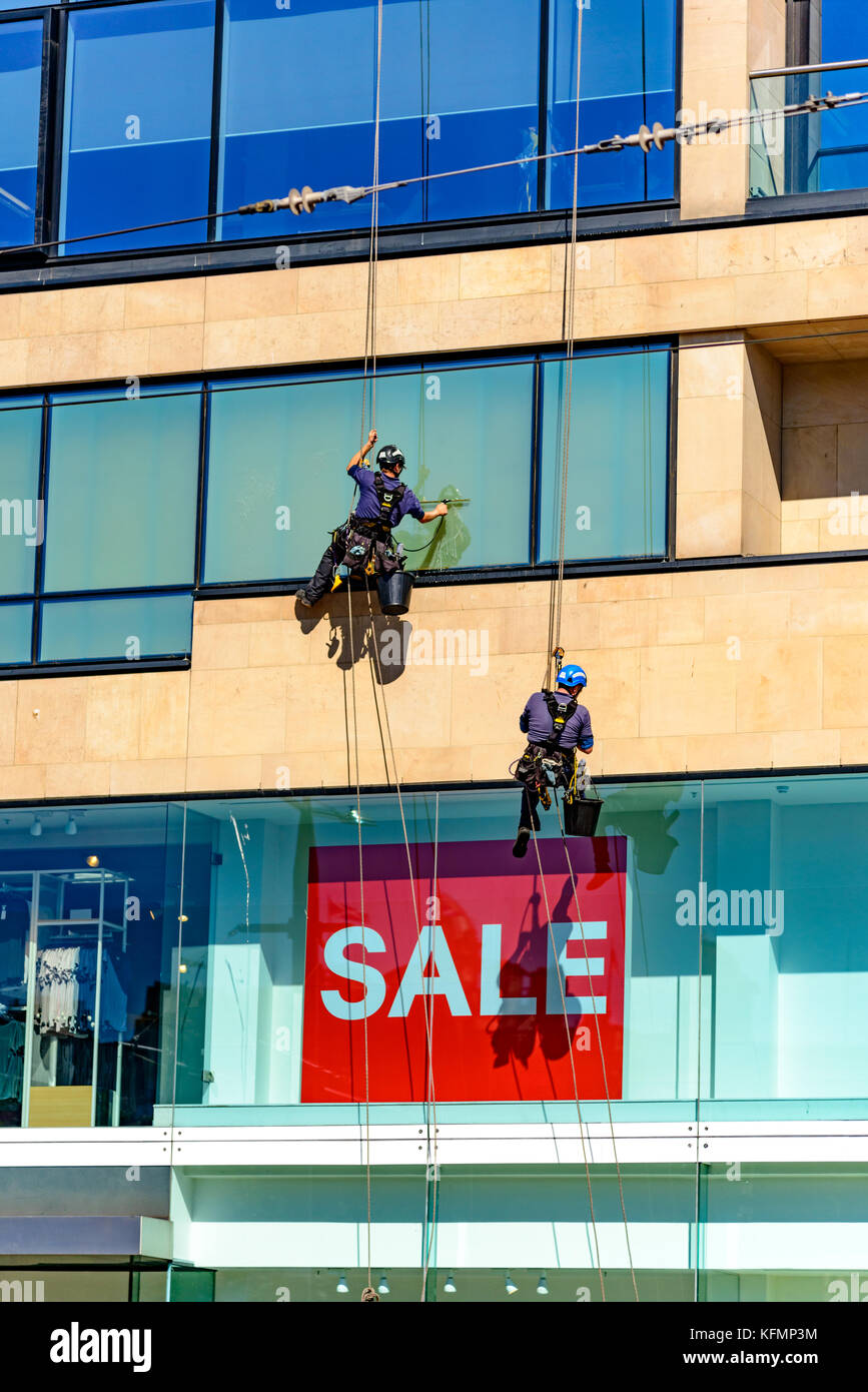 two industrial window cleaners on tall shop building Stock Photo - Alamy