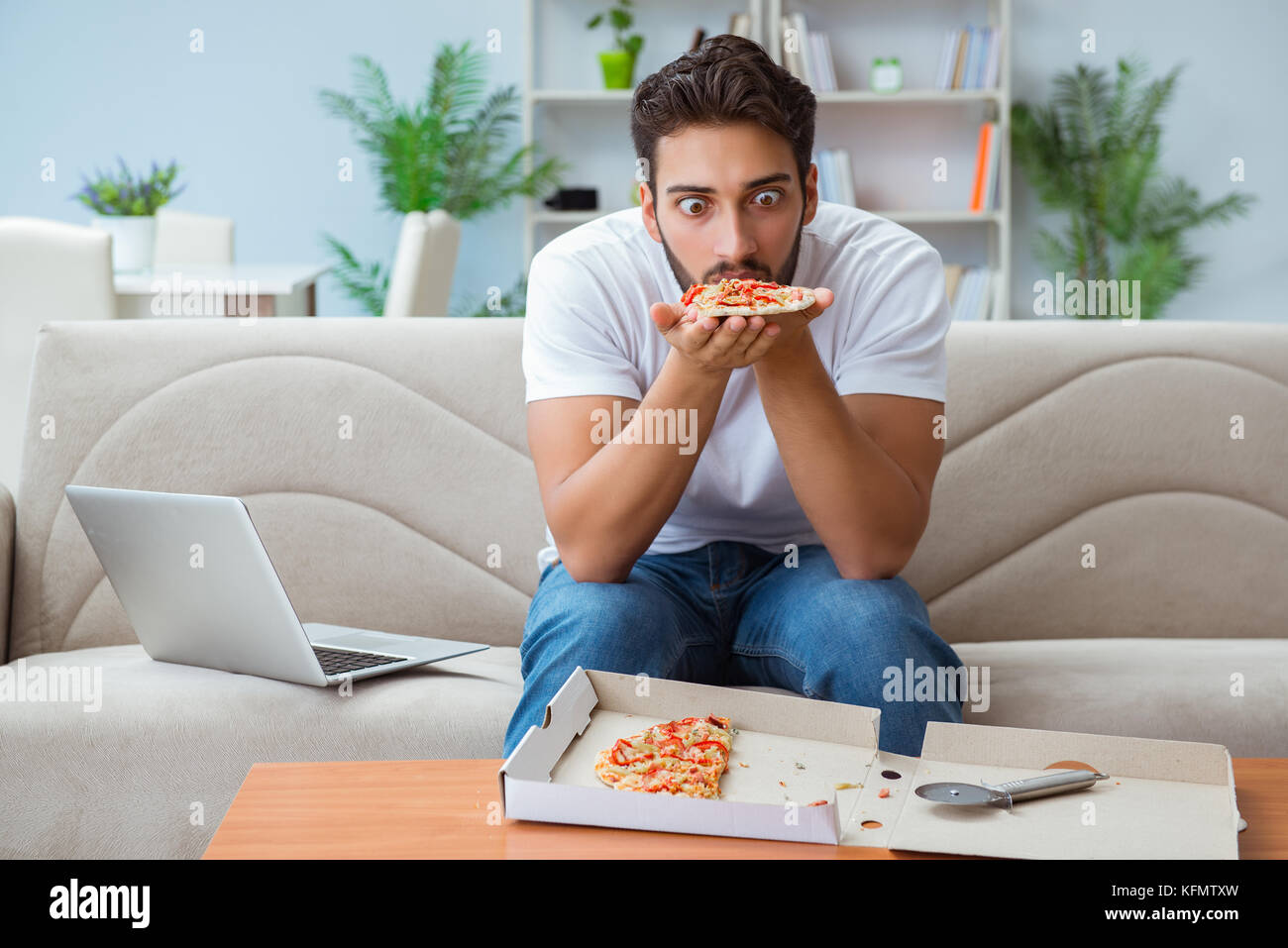 Man eating pizza having a takeaway at home relaxing resting Stock Photo ...