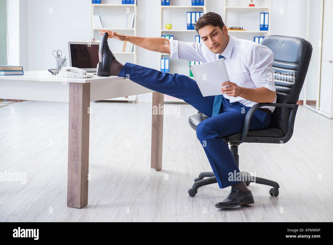 Young businessman doing sports stretching at workplace Stock Photo - Alamy