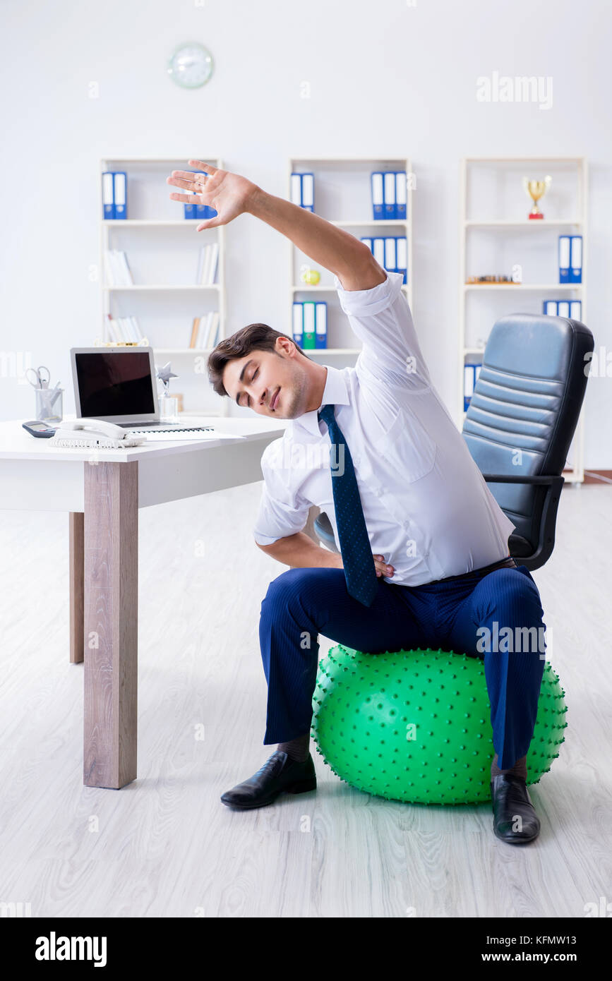 Young businessman doing sports stretching at workplace Stock Photo - Alamy