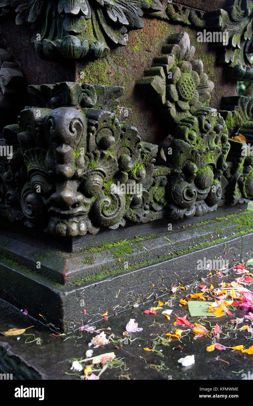 Balinese stone carving with flower petals Stock Photo - Alamy