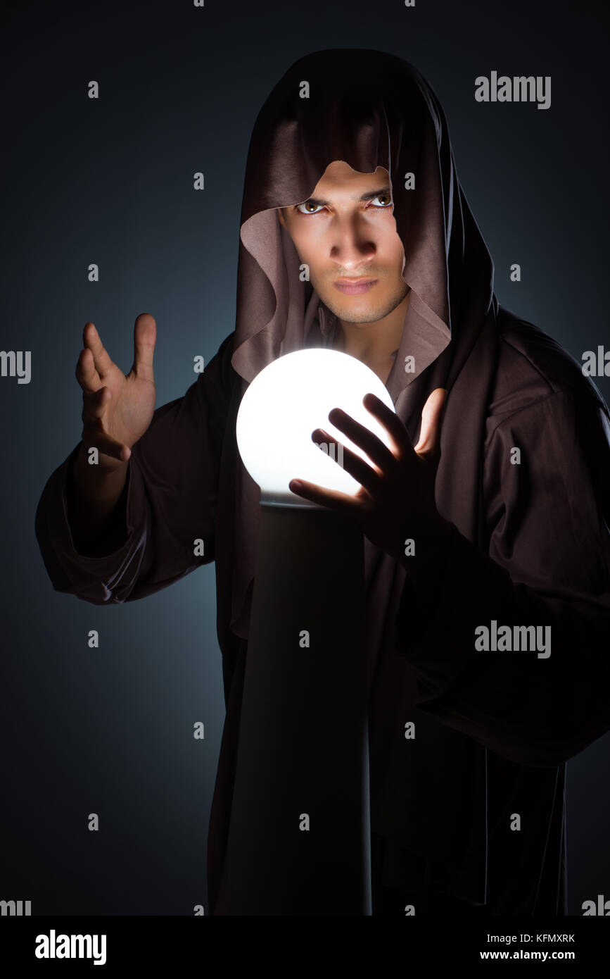 Young wizard with crystal ball in dark room Stock Photo - Alamy