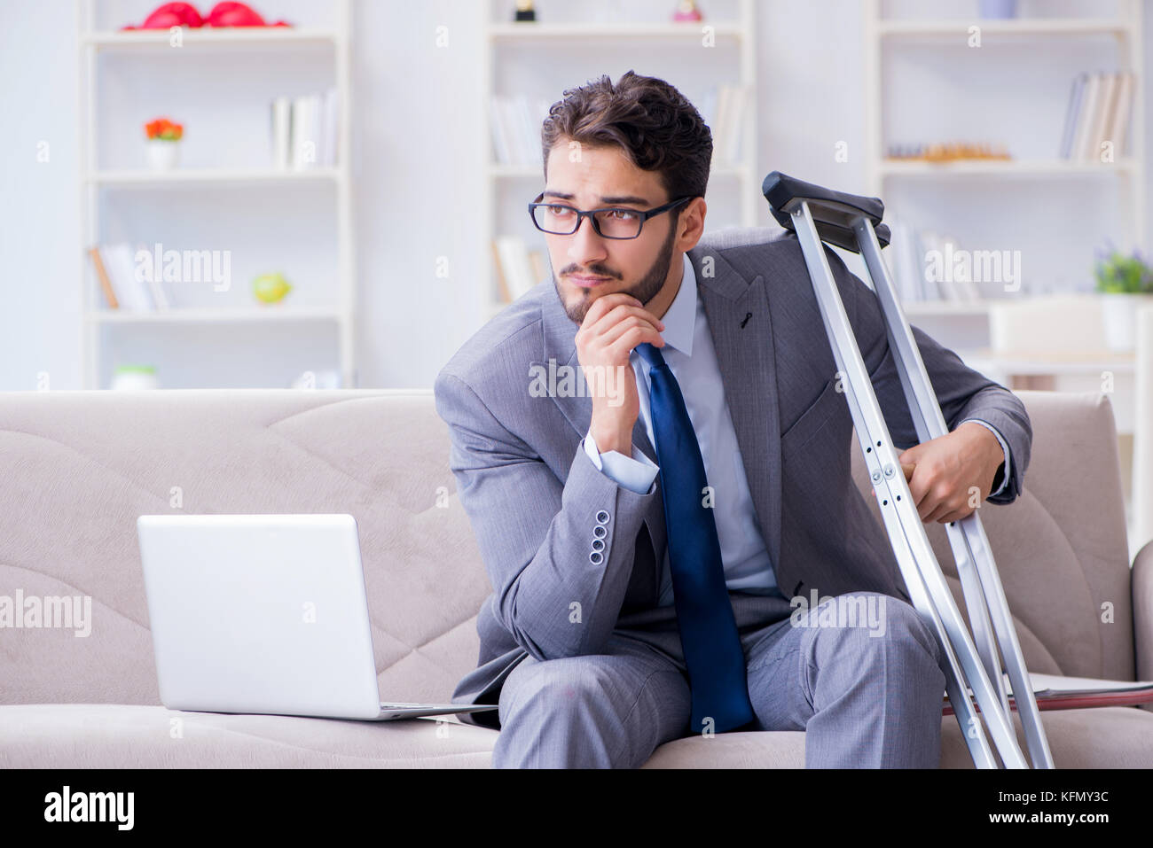 Businessman with crutches and broken leg at home working Stock Photo ...